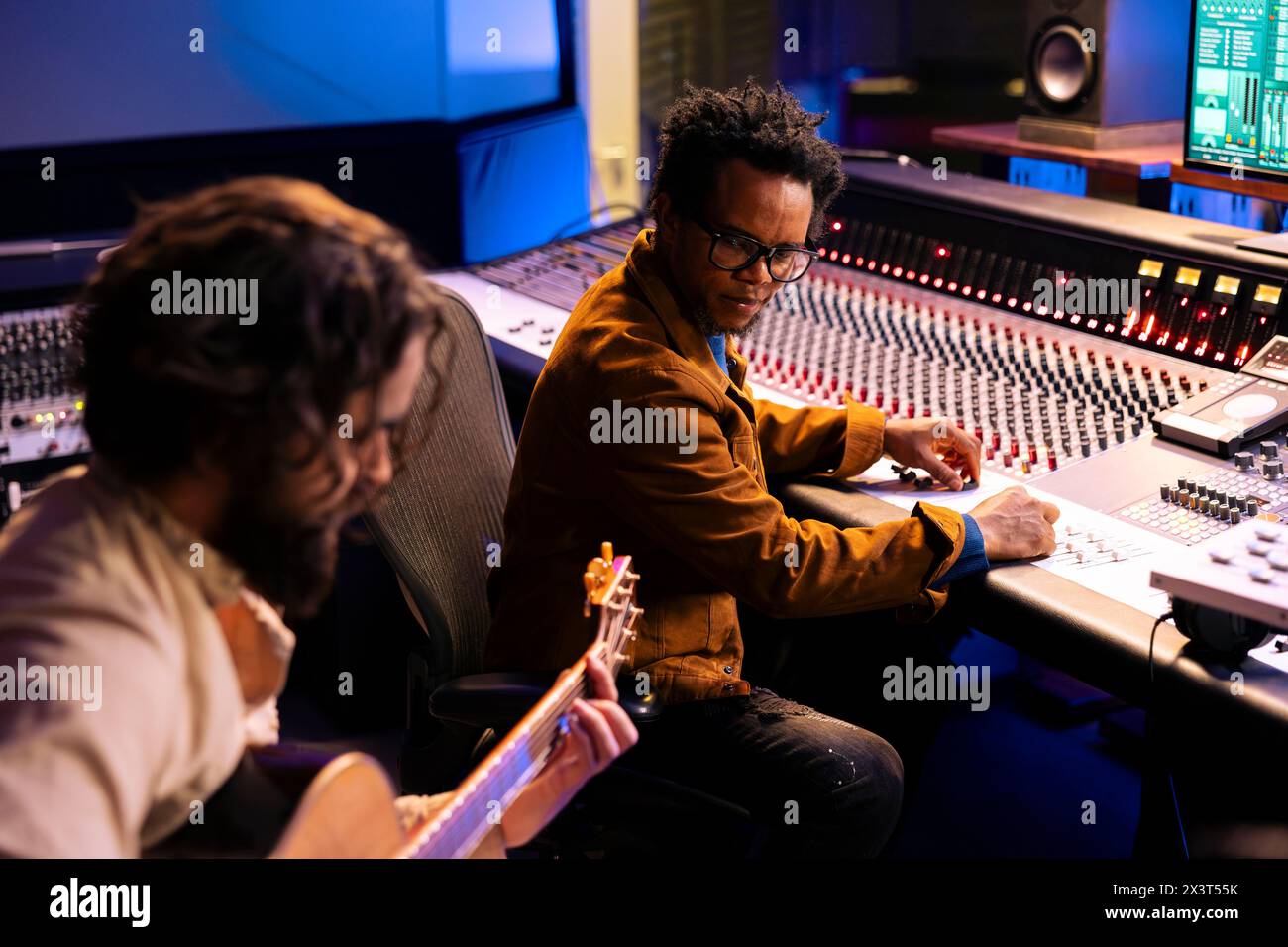Artist playing a new record on his guitar in control room, recording ...