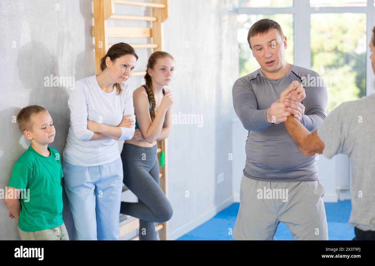 Man coach shows family students technique of performing painful modus ...
