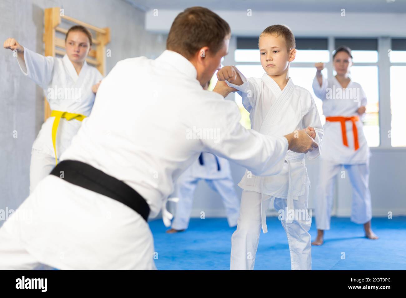 Teacher corrects boy pupil pose posture position of body, hands, legs ...