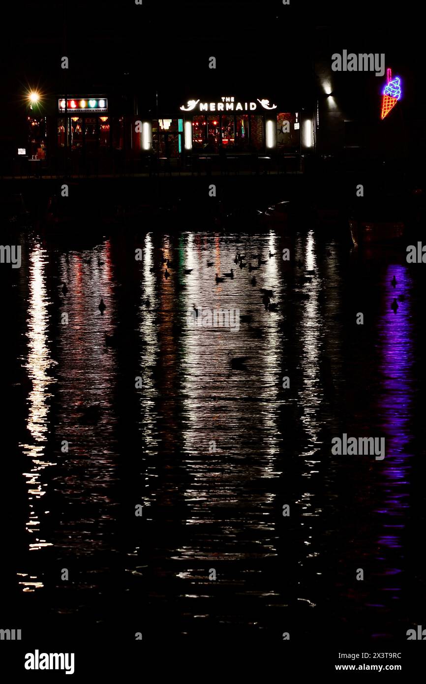 Lights from The Mermaid Restaurant reflect across the water at high ...