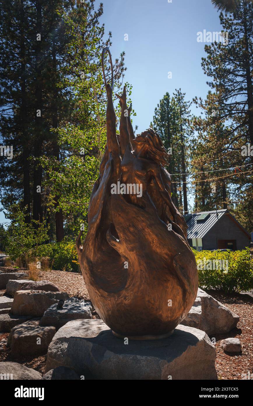 Bronze sculpture of flame shape on stone pedestal in natural setting ...