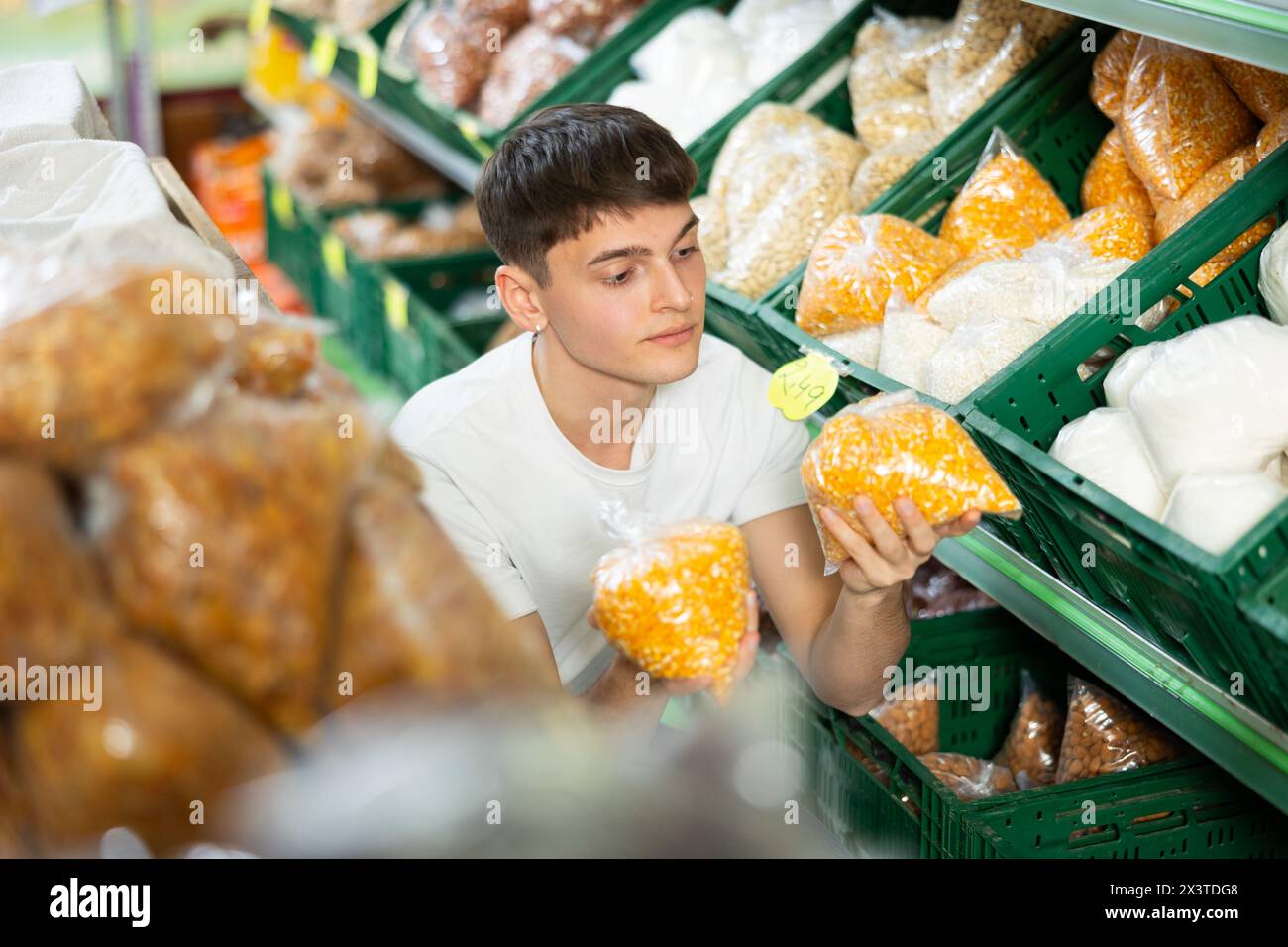 Thinking guy stands in department of supermarket and chooses packaged ...