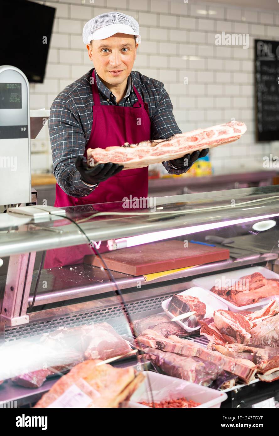 Adult man puts beef ribs in showcase Stock Photo - Alamy