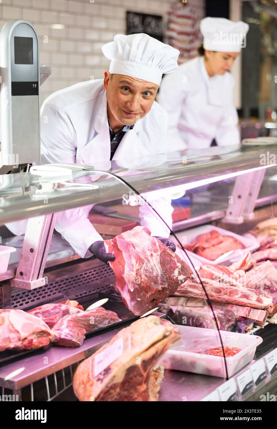 Adult man puts beef ribs in showcase Stock Photo - Alamy