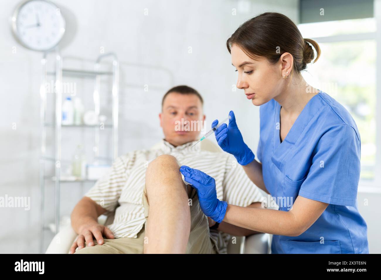 Female doctor performs intra-articular injection treatment of knee ...