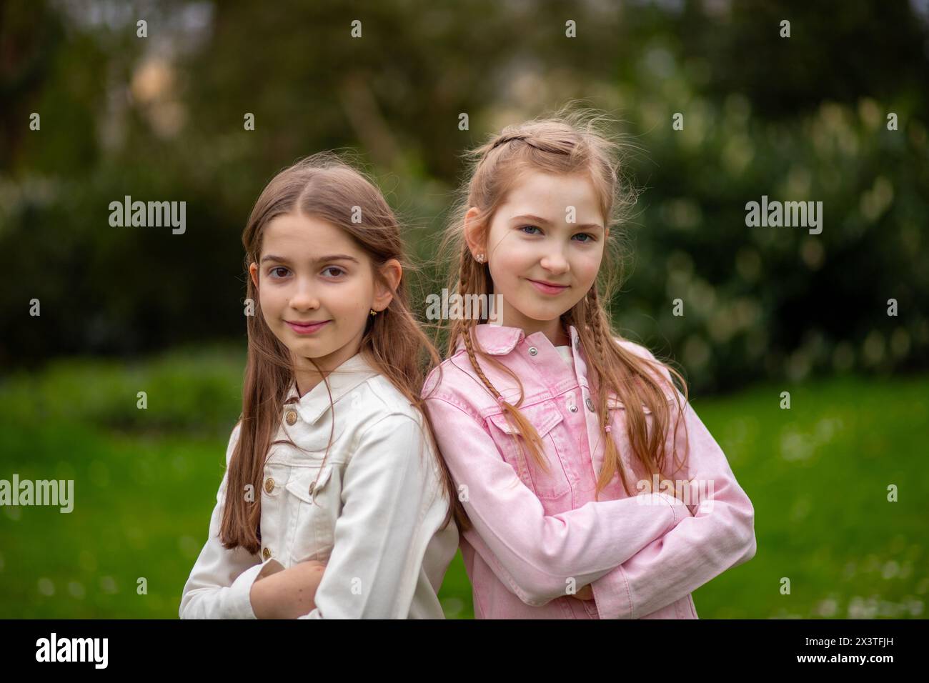Two charming girls in pastel-shaded outfits, smiling amiably and posing ...
