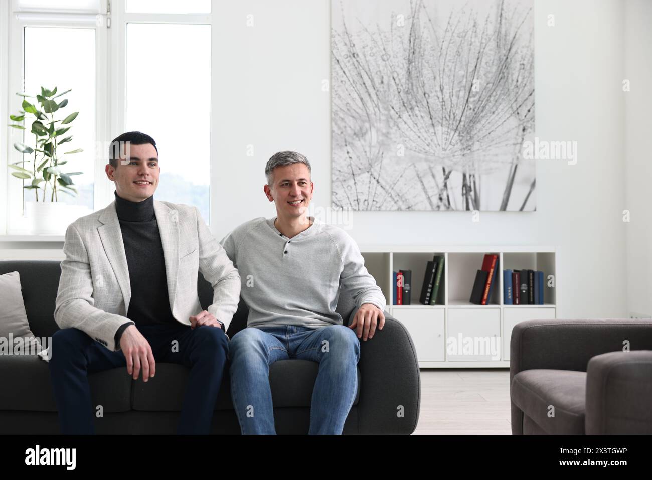 Happy men sitting on sofa at home Stock Photo - Alamy