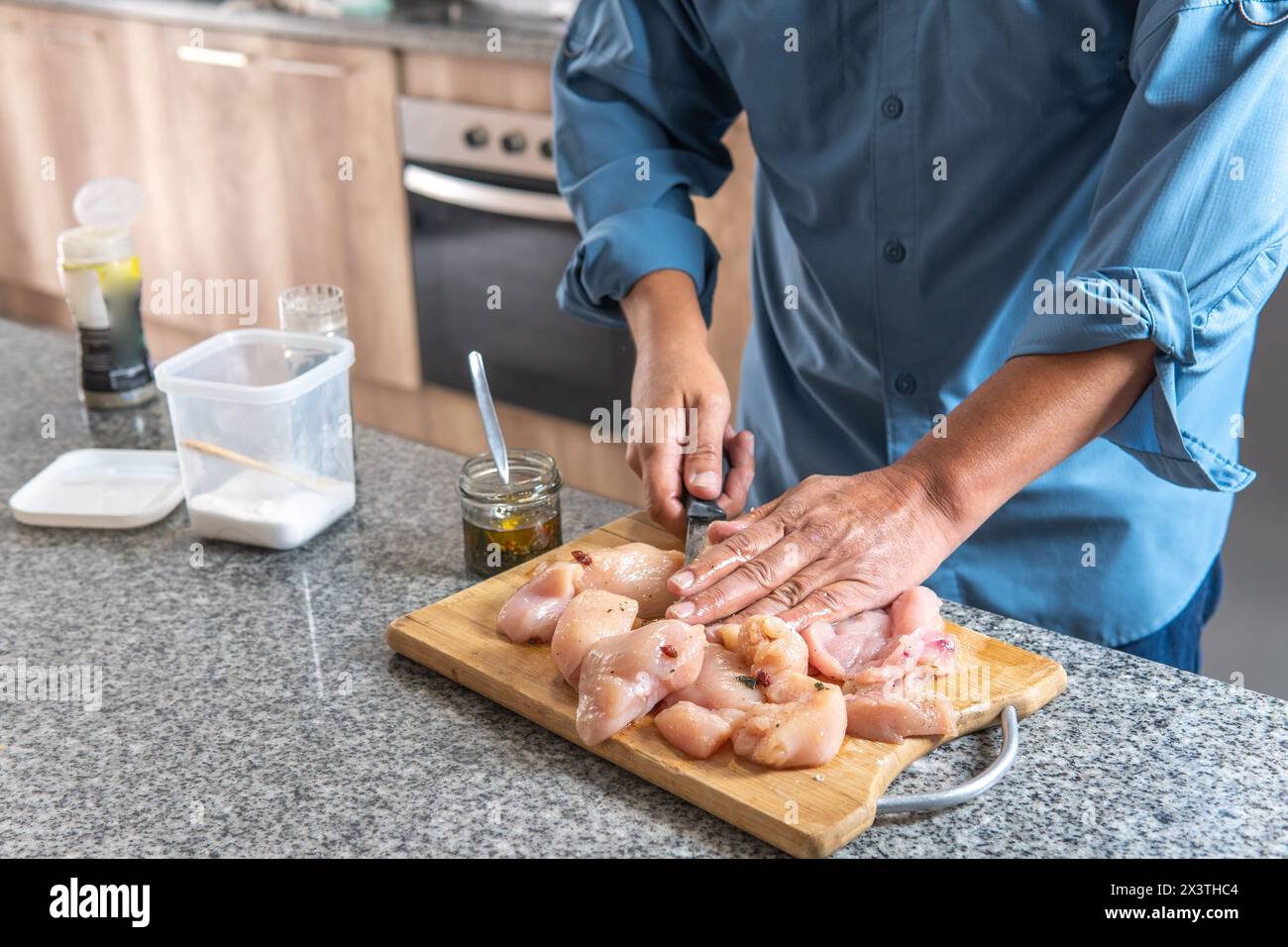 unrecognizable chef cutting chicken to prepare a recipe on the kitchen ...