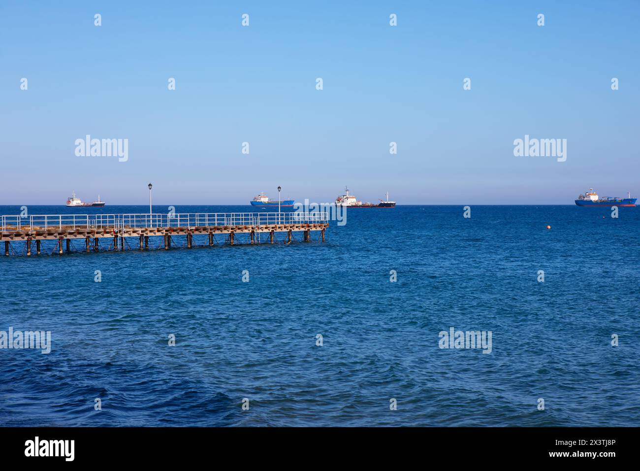 Pier in the sea with ships in the distance on the horizon. Blue sky ...