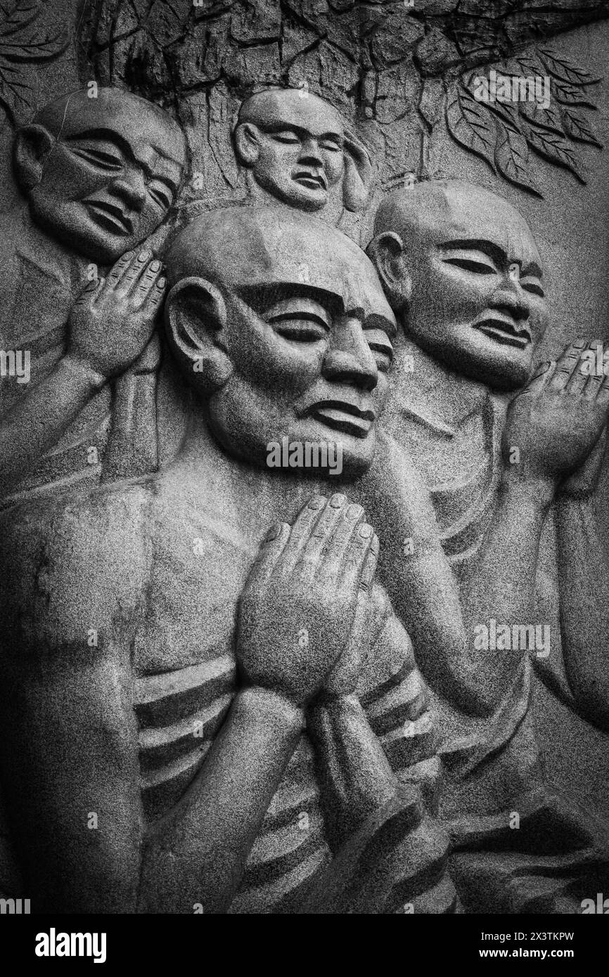A group of Buddhist monks praying statues in front of a reclining ...