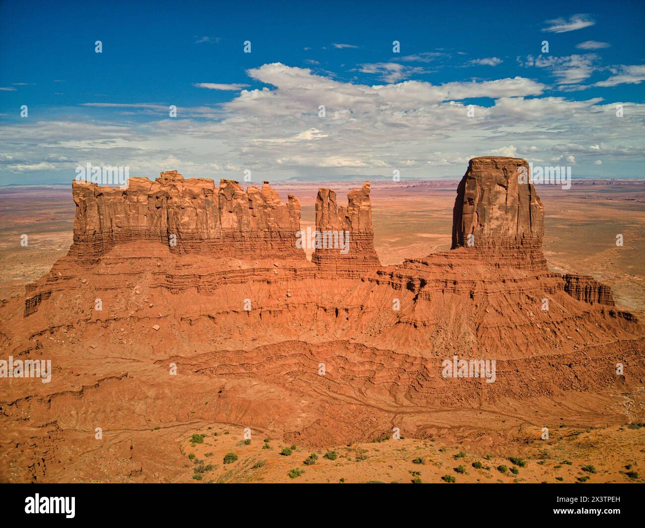 A massive rock formation stands prominently in the arid desert ...