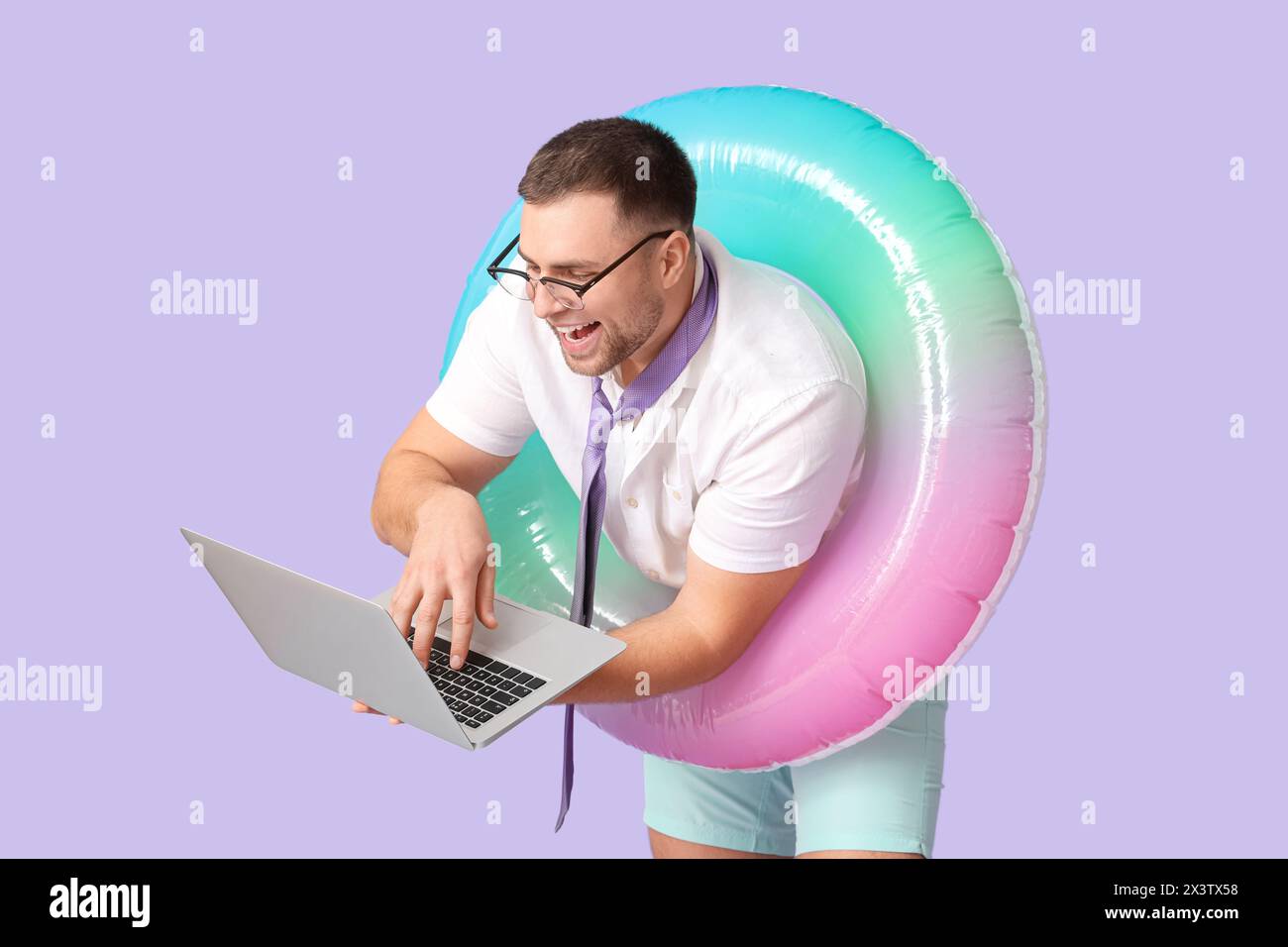 Happy office worker with laptop and inflatable ring on lilac background ...
