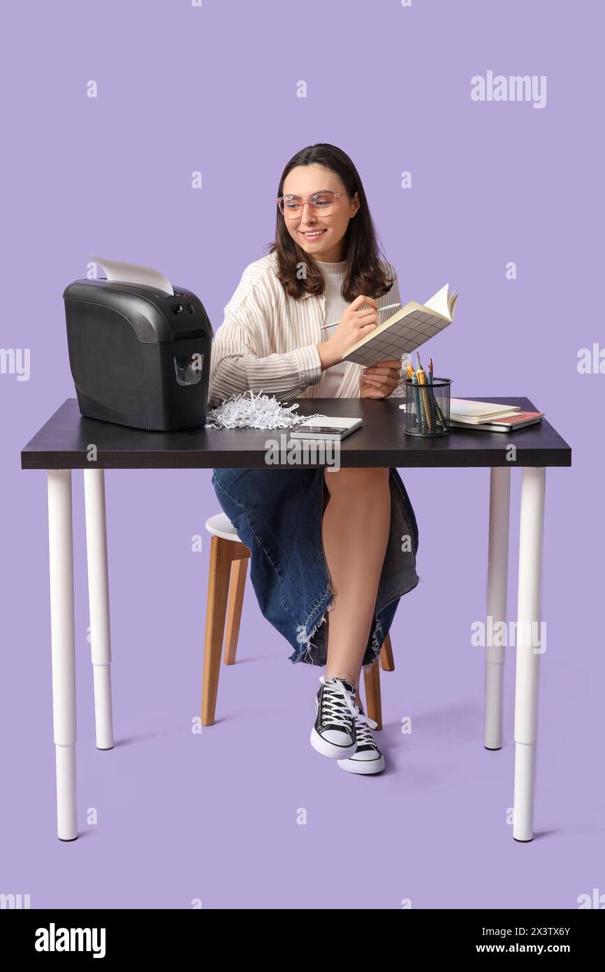 Secretary destroying document in shredder on lilac background Stock ...