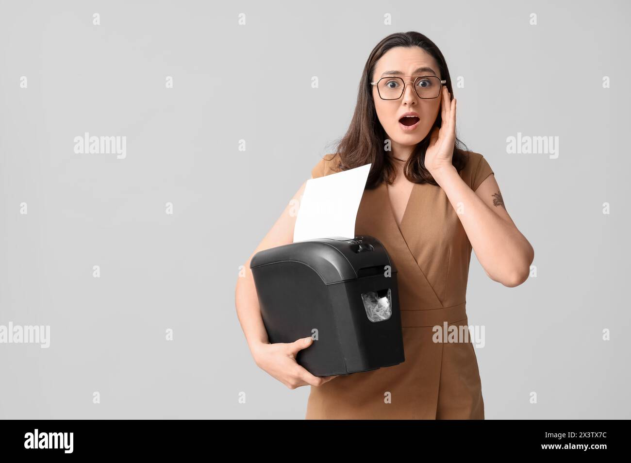 Shocked secretary with shredder on light background Stock Photo - Alamy