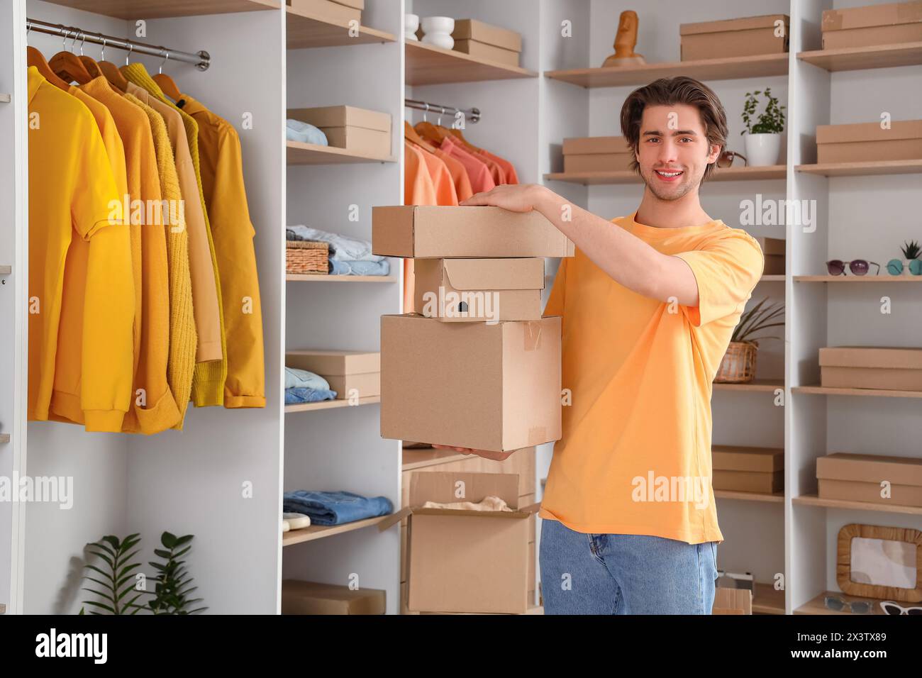 Handsome young happy man with wardrobe boxes and stylish clothes in ...