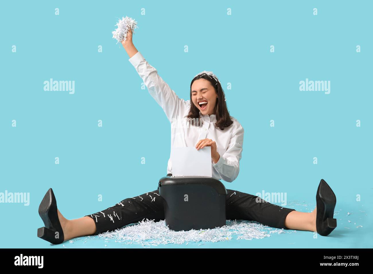 Happy secretary with shredder and pieces of paper sitting against blue ...