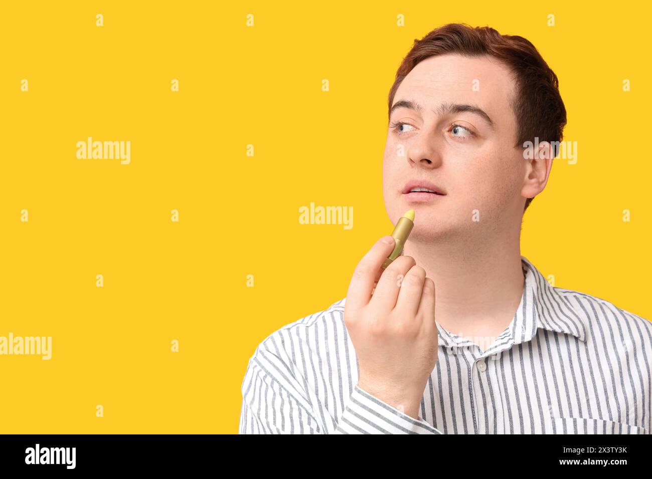 Handsome young man applying lip balm on yellow background Stock Photo ...
