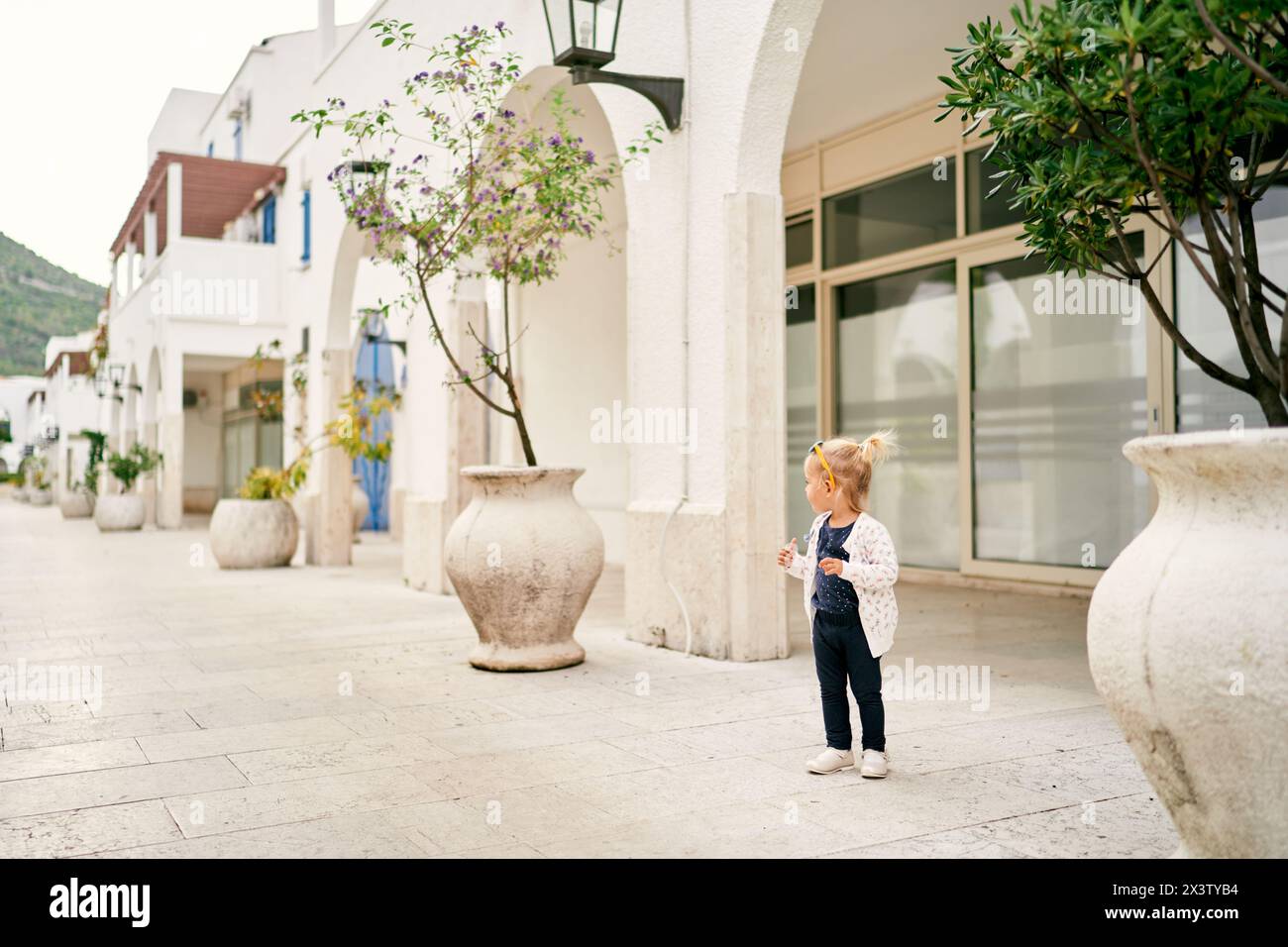 Little girl stands near an apartment building and looks away Stock ...