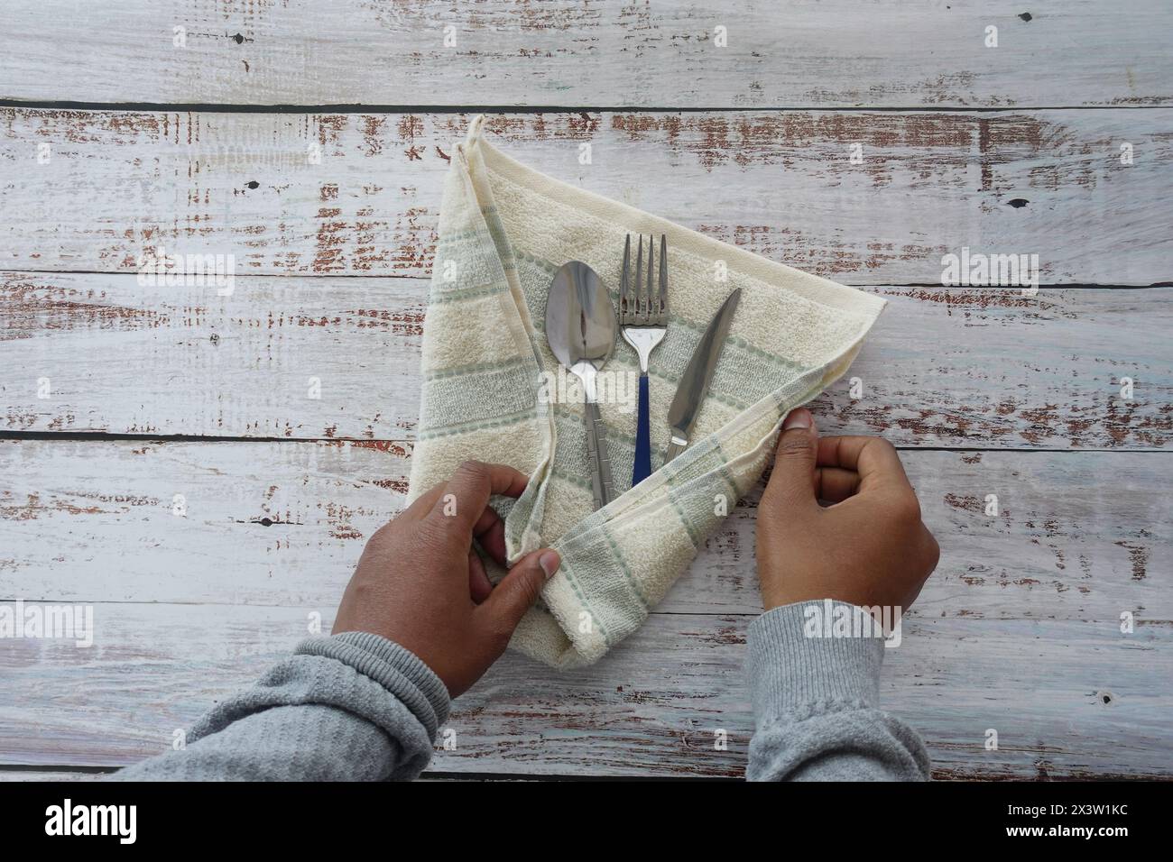 person hand cleaning and drying cutlery with a towel Stock Photo - Alamy