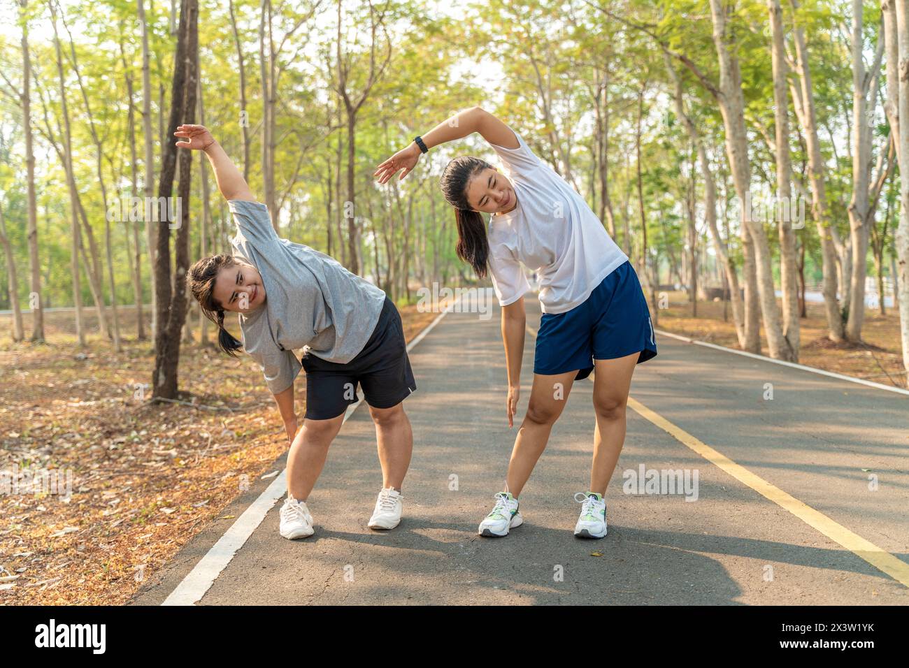 Two young female friends stretching their arms and legs before starting ...