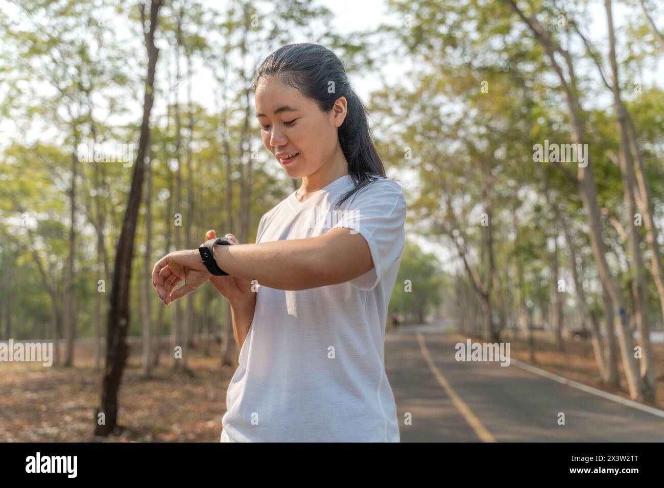 Happy young woman checking her run time on her smart watch after ...