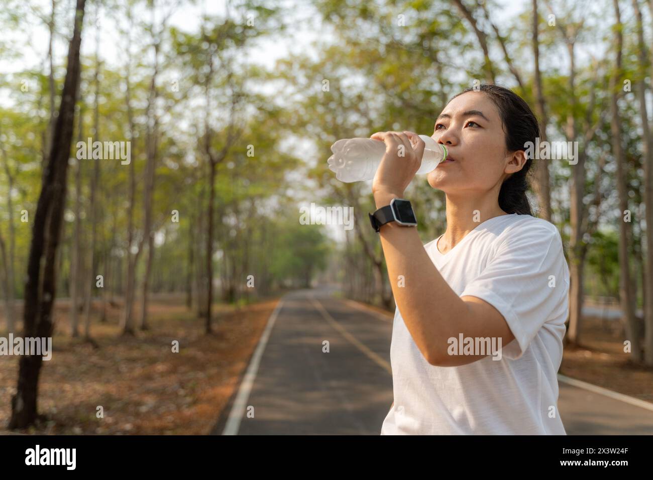 Young woman drinking water from a plastic bottle after her morning run ...