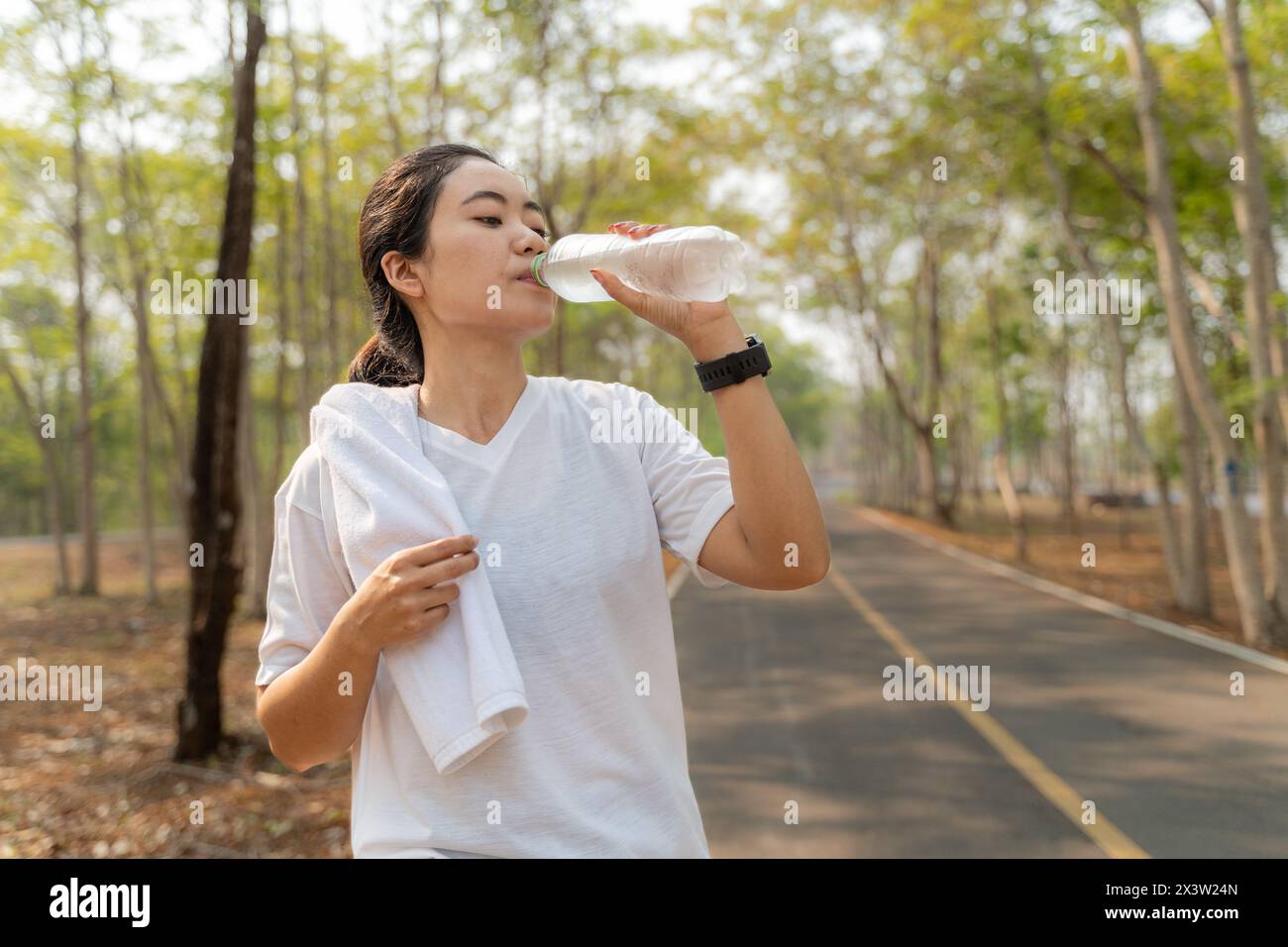 Young woman drinking water from a plastic bottle after her morning run ...