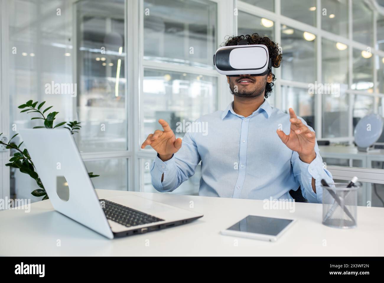 Curly-haired young professional immersed in virtual reality using a VR ...