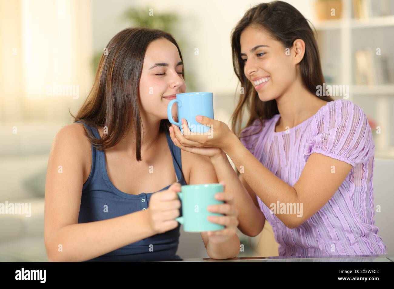 Two friends drinking coffee and smelling at home Stock Photo - Alamy