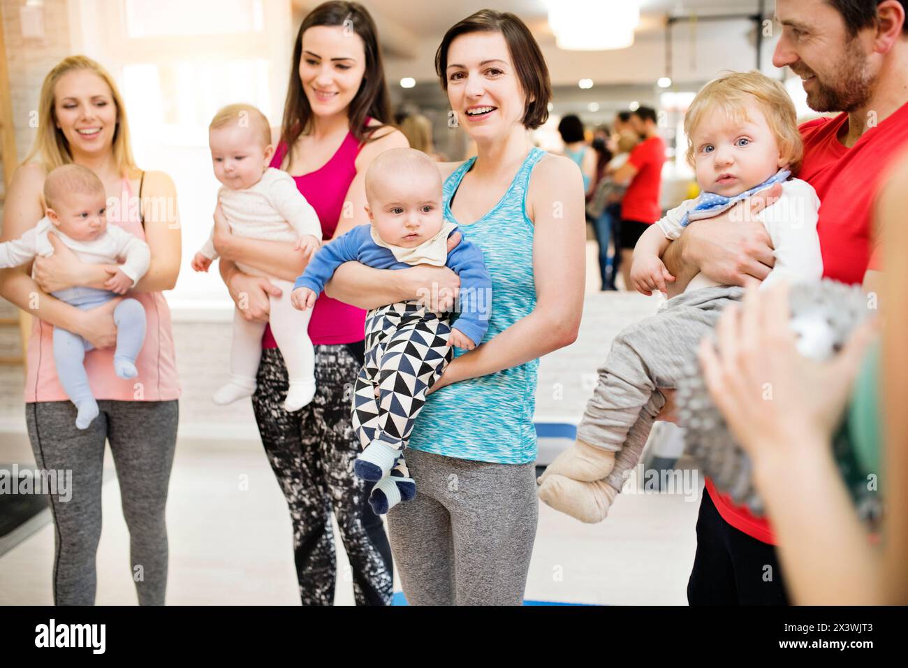 Group exercise class, mother working out with baby in gym. Moms staying ...