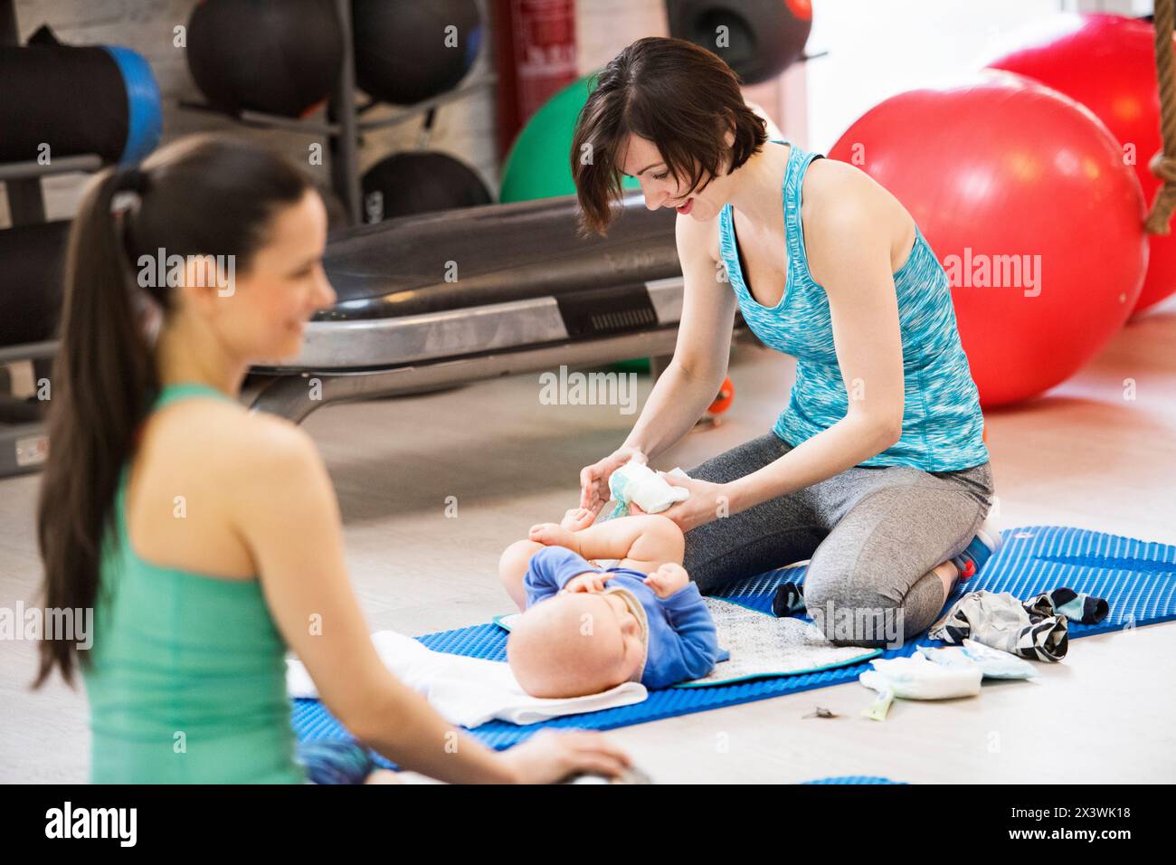 Mother changing diaper during group exercise class. Moms staying active ...