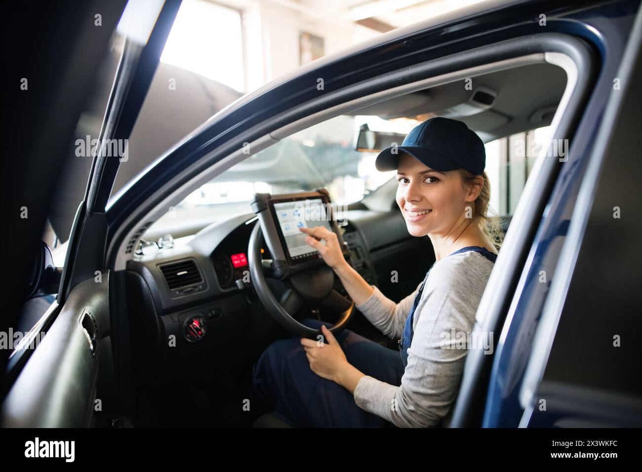 Female auto mechanic using diagnostic tool, scanner, running diagnostic ...