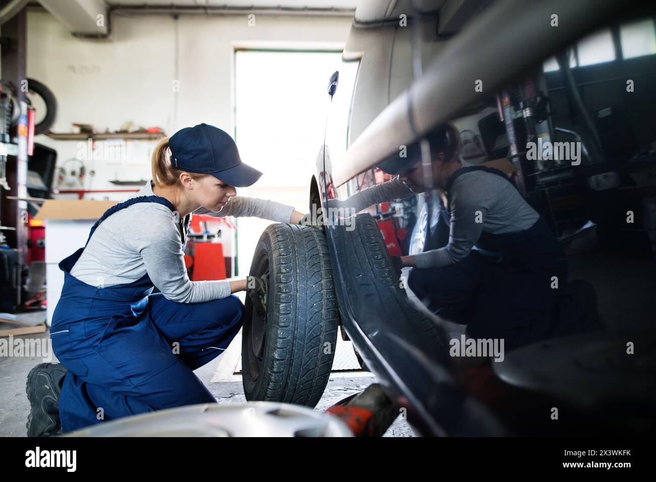 Female auto mechanic changing tieres in auto service. Beautiful woman ...