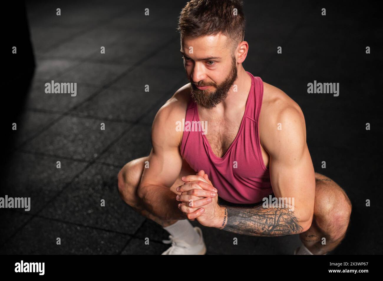 Portrait of handsome muscular man stretching his body in gym. Routine ...