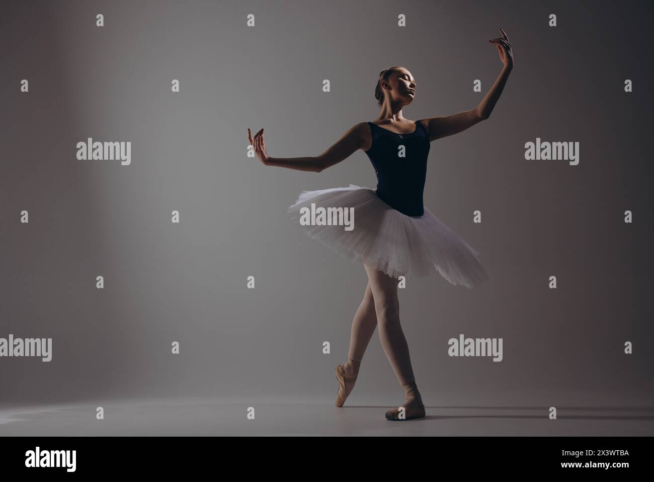 Young ballerina in elegance white tutu and pointe shoes dancing against ...