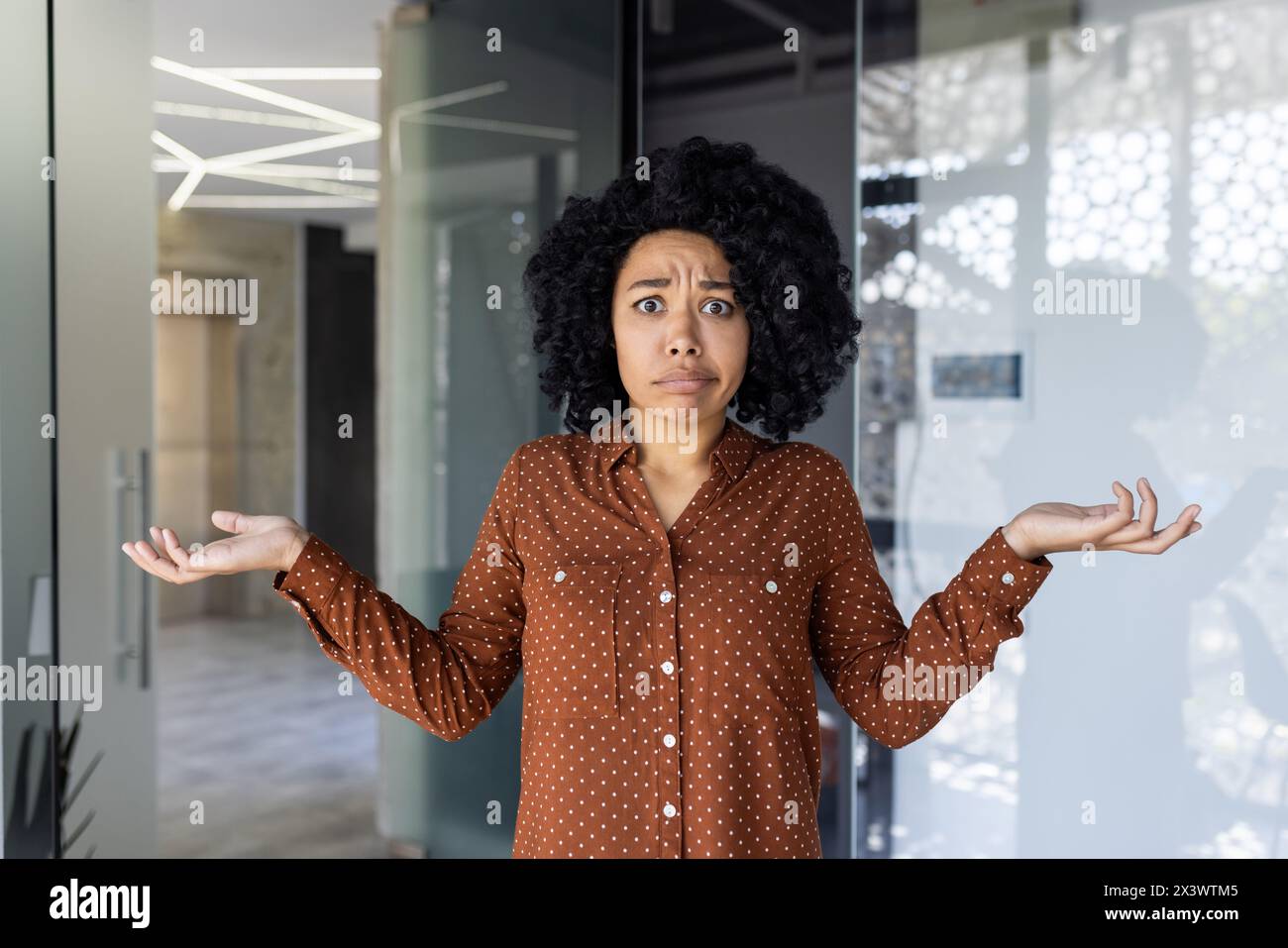 A young African American woman looking puzzled, standing in a modern ...