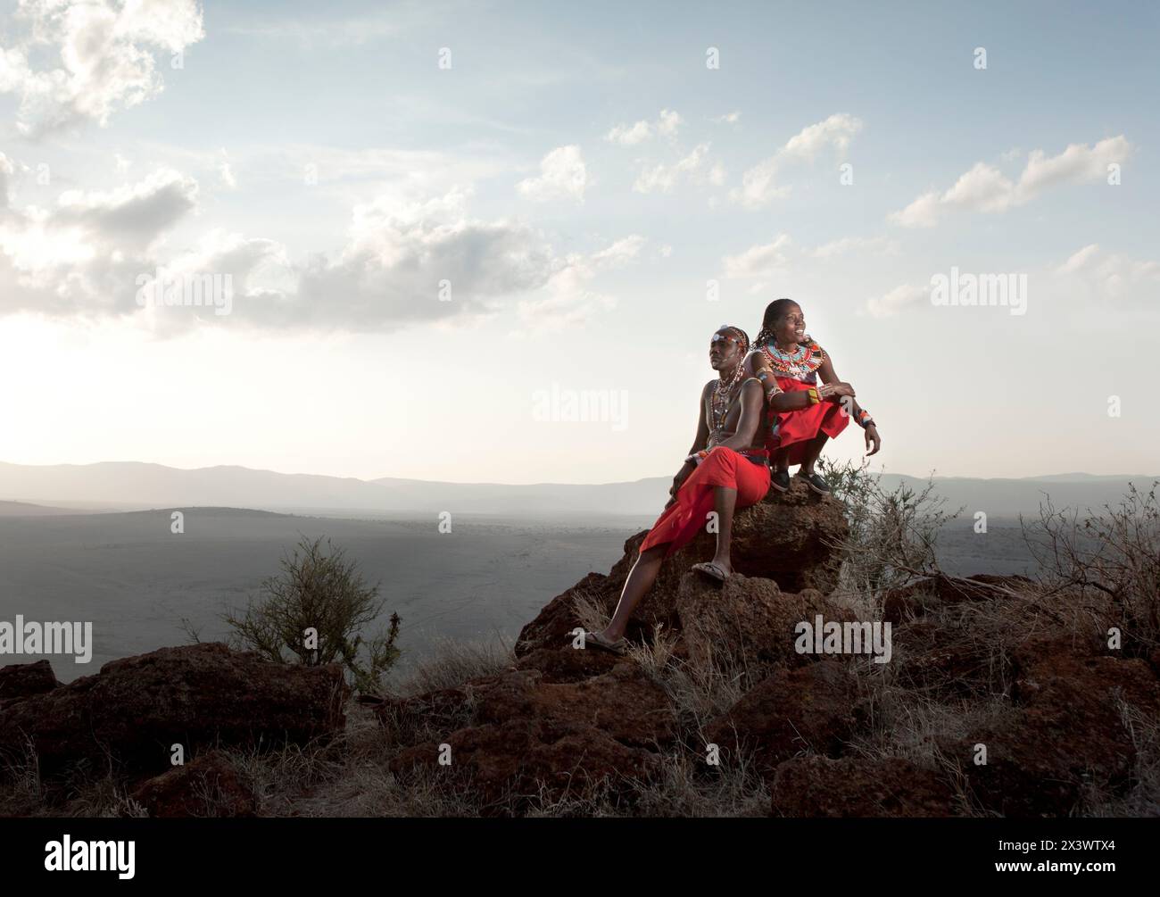 Two Kenyan safari guides rest on a rock on a hilltop in Lewas ...