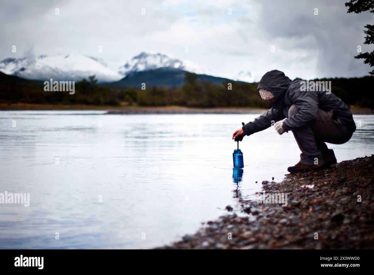 Man filling up water bottle in a cold river in Patagonia, Argentina ...