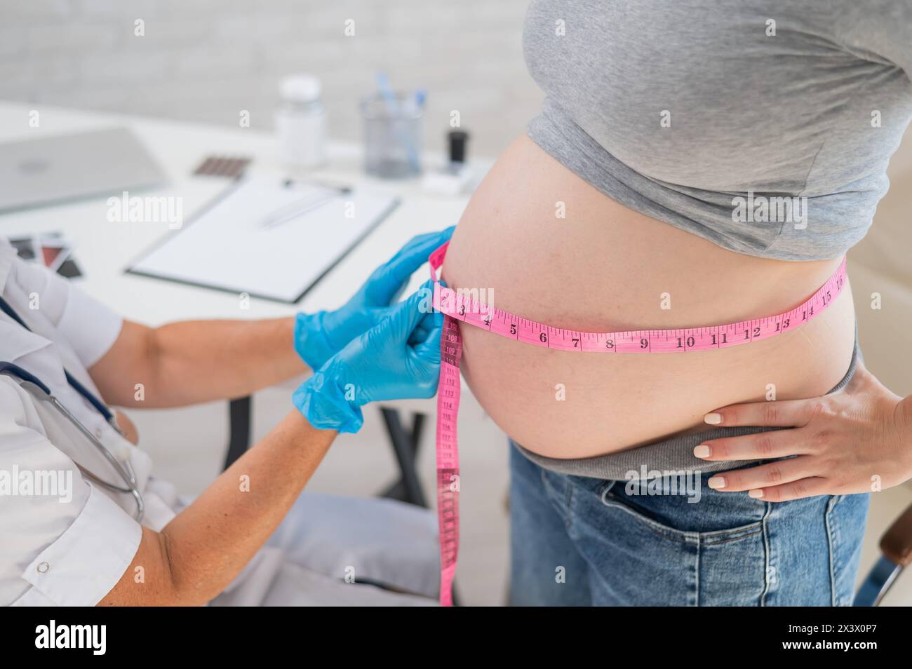 Doctor measuring the volume of a pregnant woman's abdomen using a tape ...