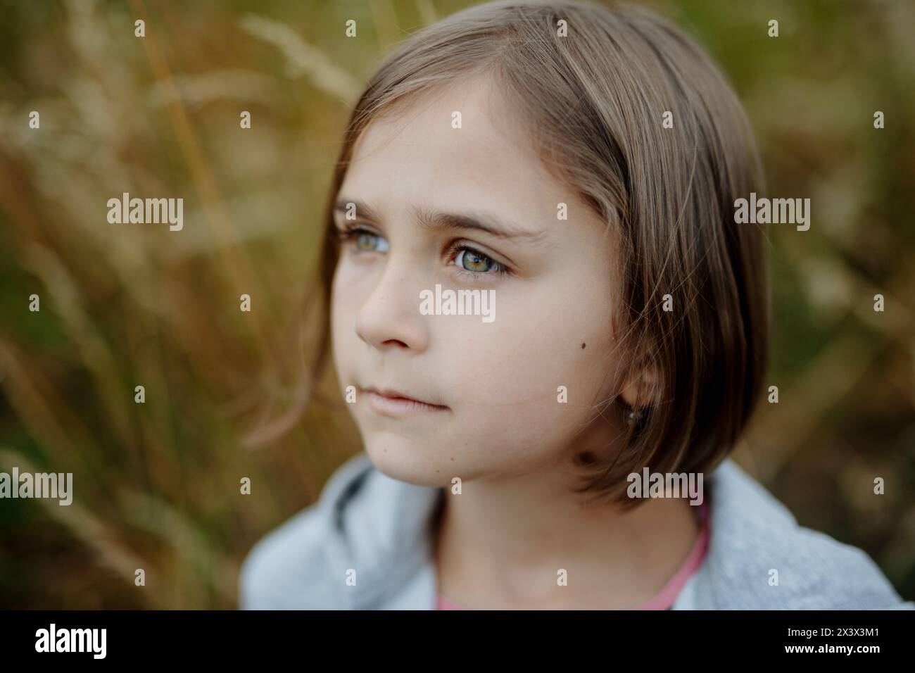 Portrait of beautiful young girl standing in nature, in the middle of tall grass, headshot. Copy ...