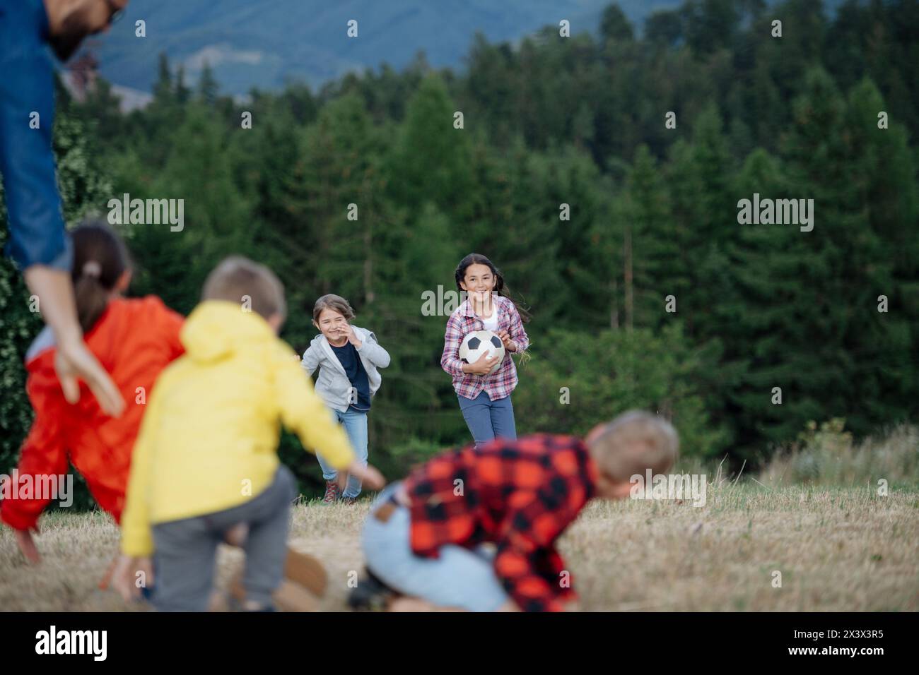 Young students playing with teacher outdoors, in nature, during field ...