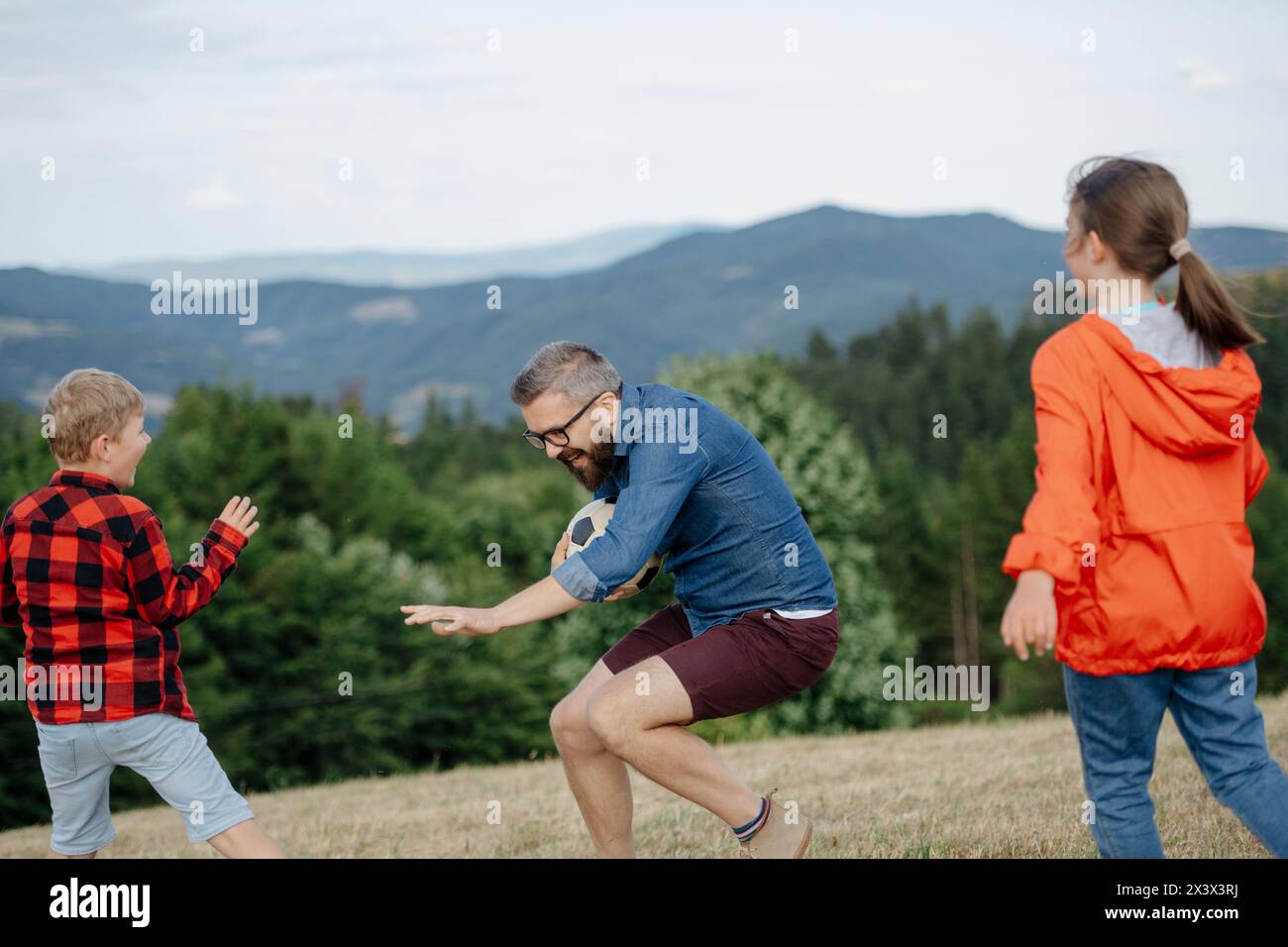 Young students playing with teacher outdoors, in nature, during field ...