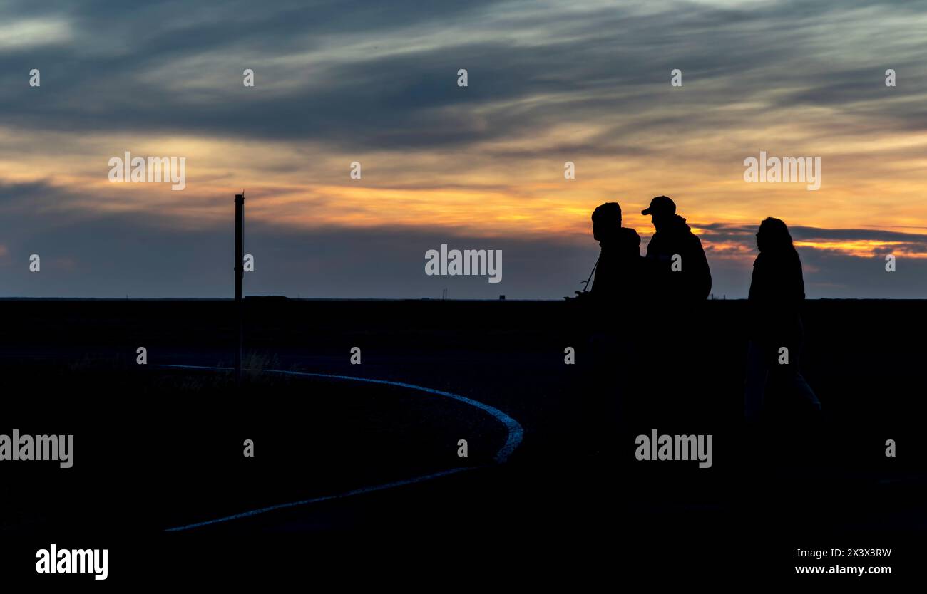 Three people walking in the dark with a sunset in the background Stock ...
