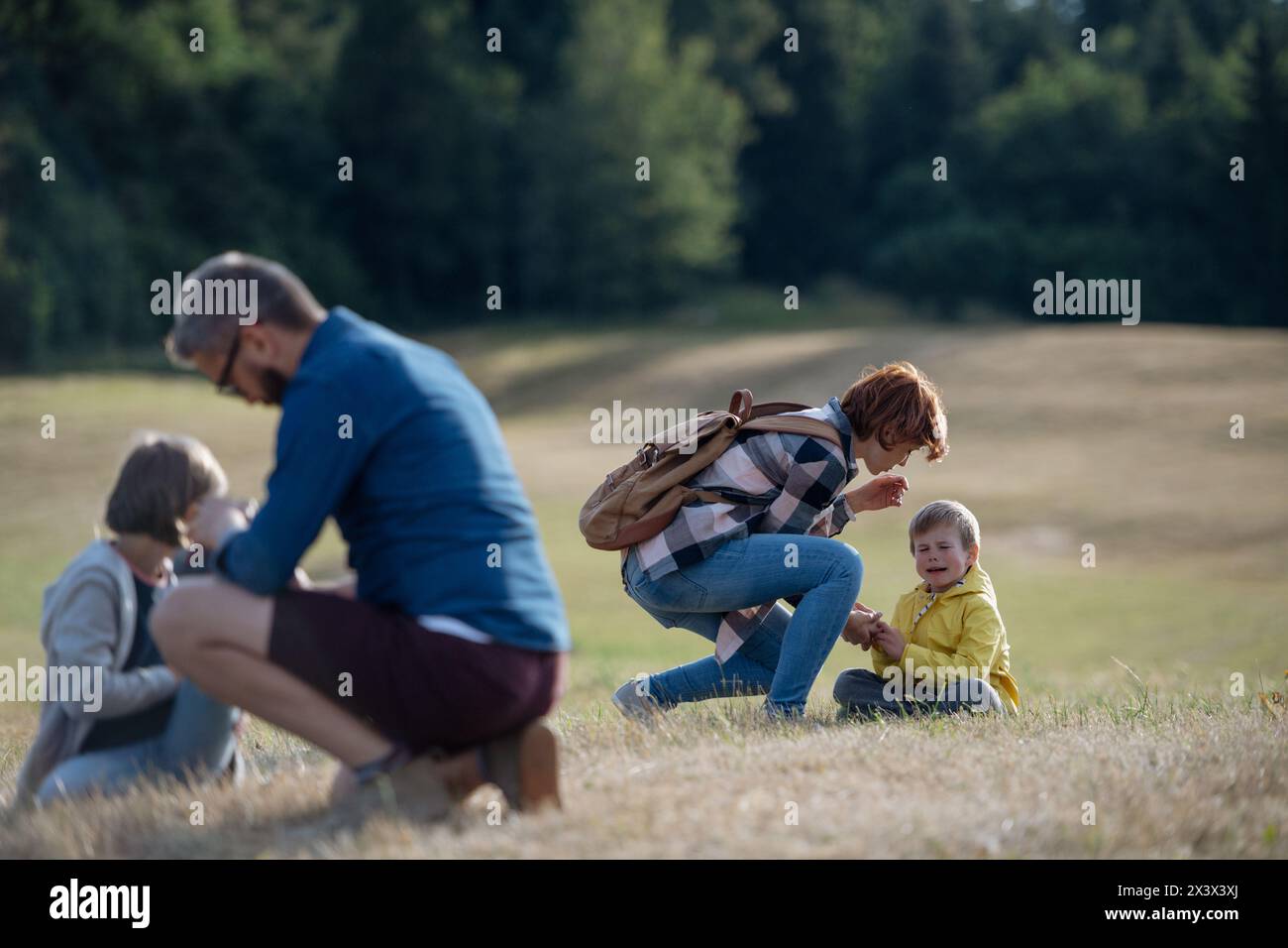 Teacher helping injured boy after fall. Young students running across ...