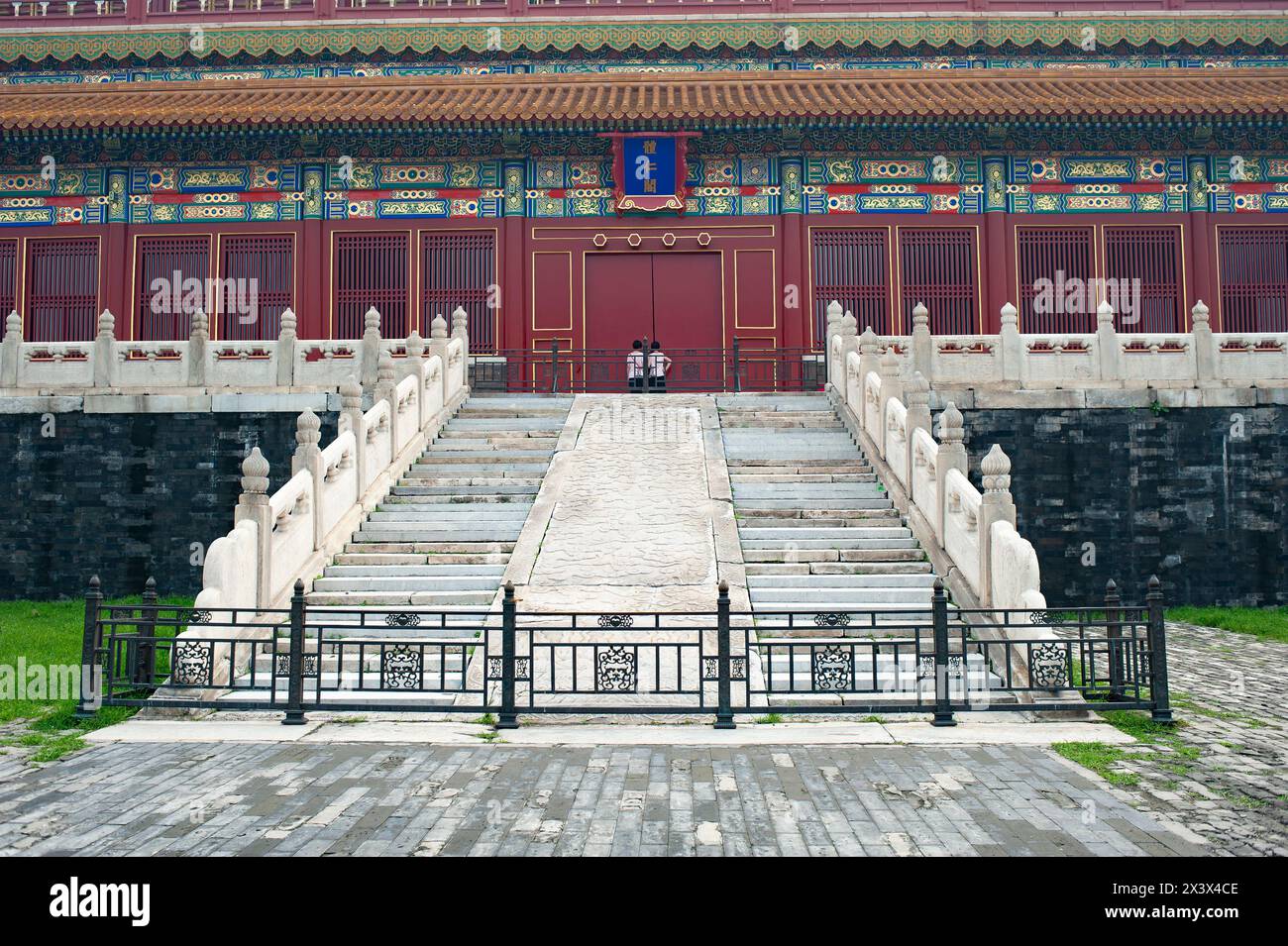 Two Chinese tourists take a peak through a gap in the door at the ...