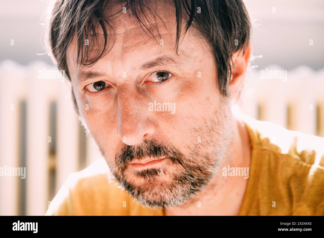 Portrait of mid adult unkempt male with beard in late 40s looking at ...