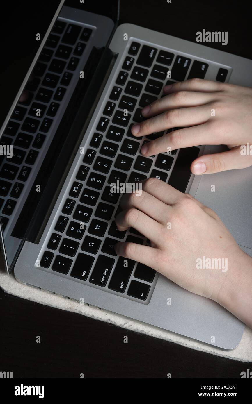 Detailed image of a young person's palms poised above a laptop keyboard ...