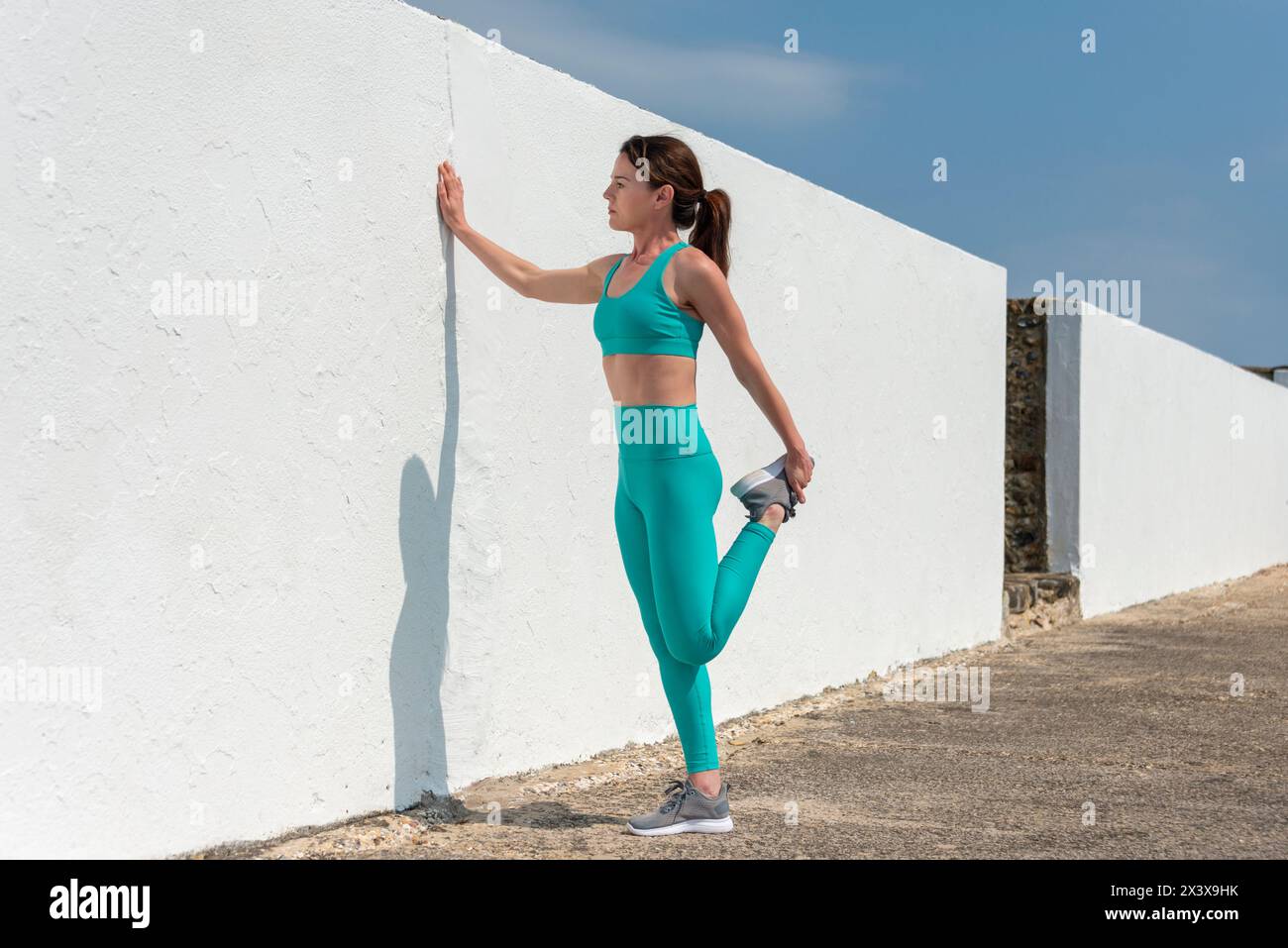 Female runner doing a leg stretch exercise outside Stock Photo - Alamy