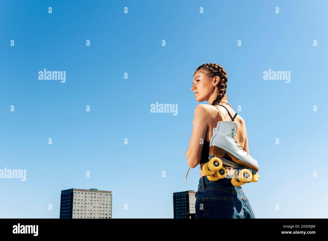 Rear view of a young woman carrying her roller skates, urban background ...