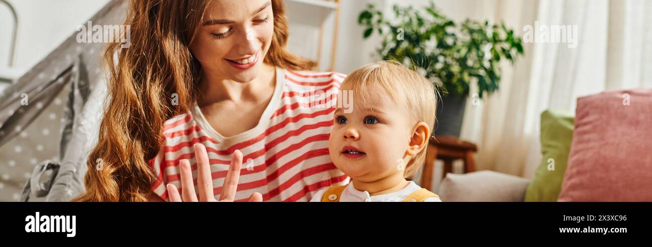 A young mother and her toddler daughter playfully engage with a ...